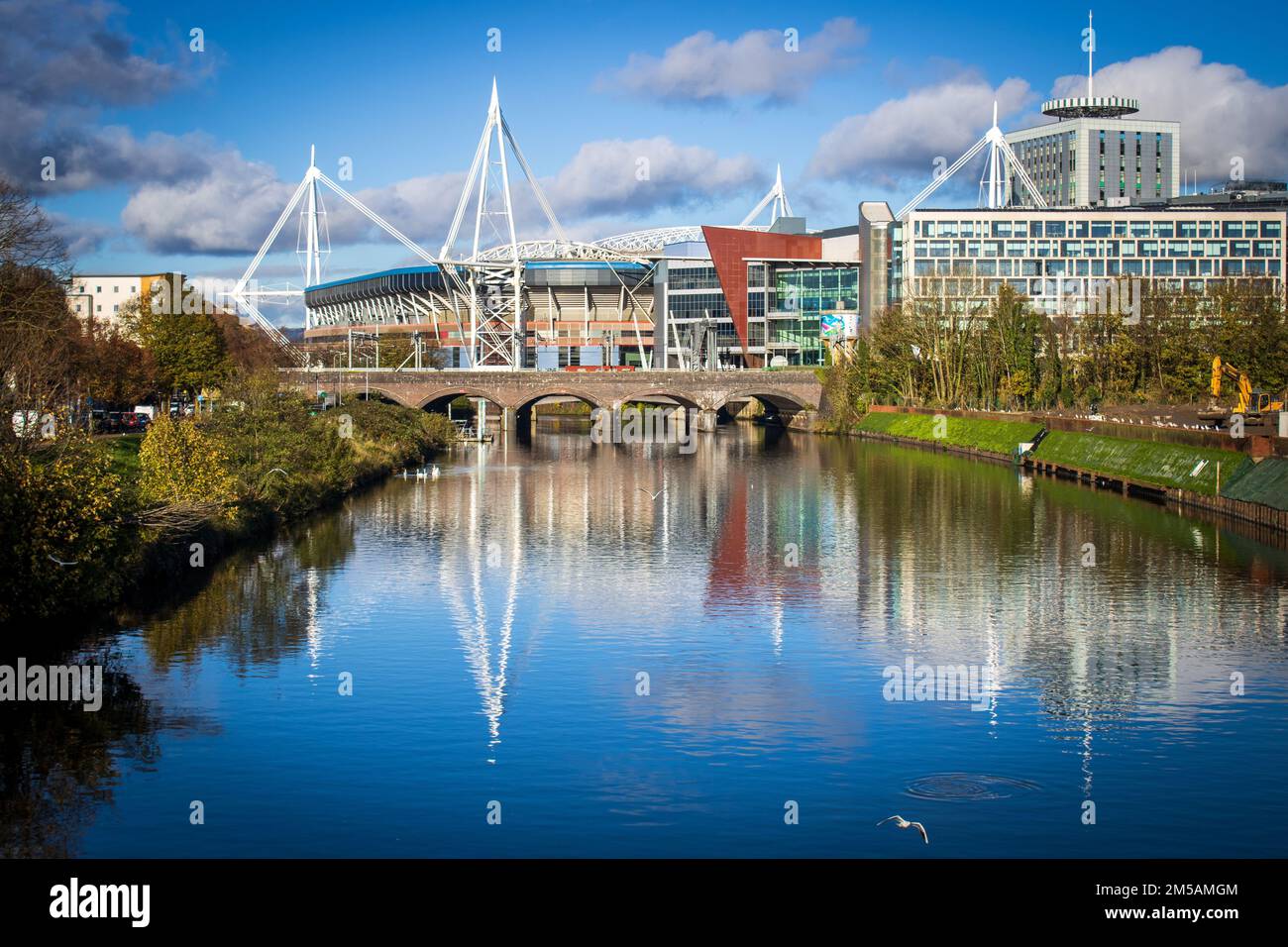 The Principality Stadium reflecting on a river with bridge under a blue ...