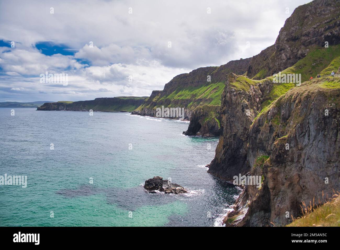 A beautiful view of a cliff and calm sea under the blue cloudy sky ...