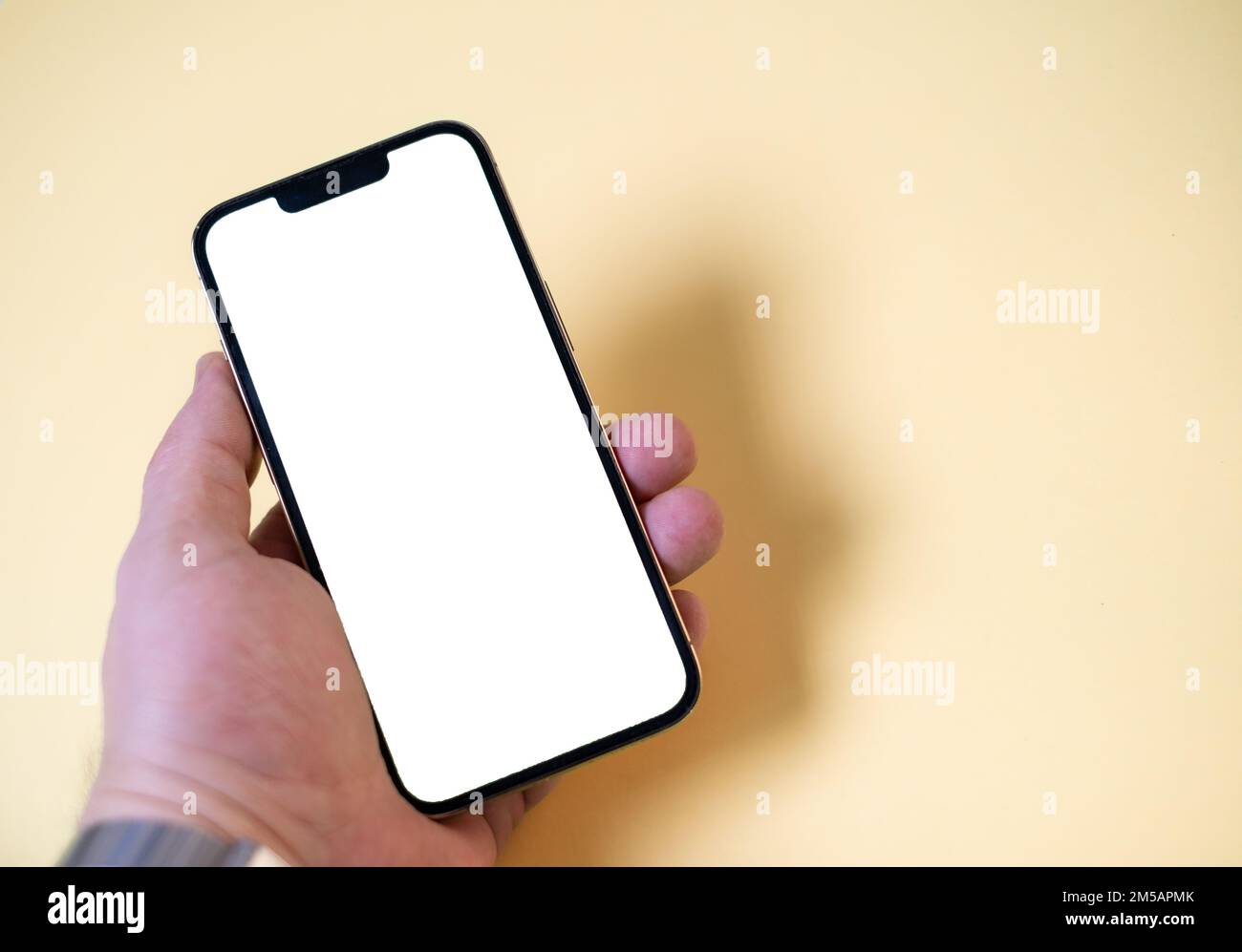 Hand holding black smartphone isolated on yellow background, white ...