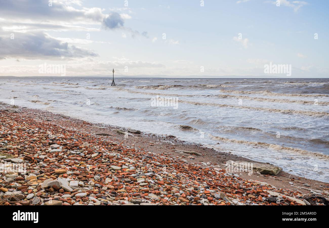 Waves crash onto the red bricks which line part of the beach at Crosby ...