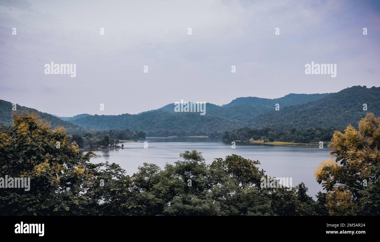 A river in a green landscape with tall mountains on the horizon in ...