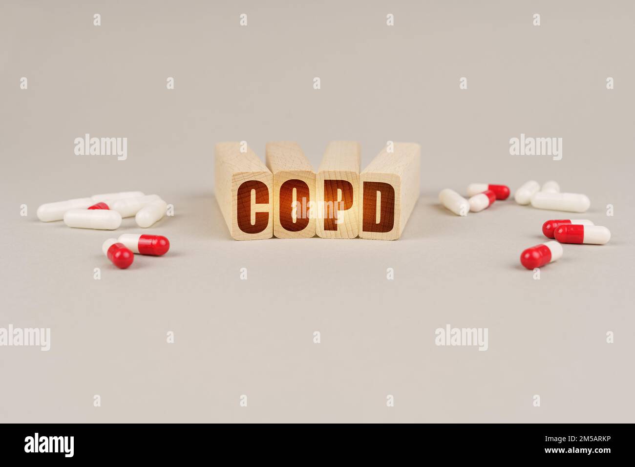 Medical concept. On a gray surface are pills and a red wooden block ...