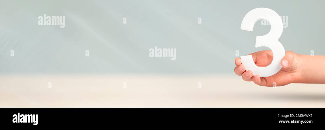 Number three in hand. Hand holding white number 3 on blurred background ...