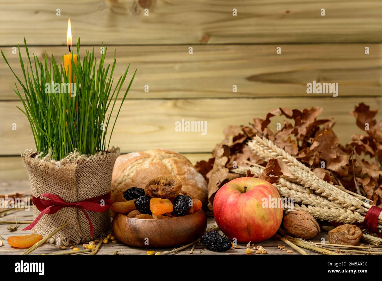 Yule log or badnjak, apple, cereals, dried fruit and a burning candle ...