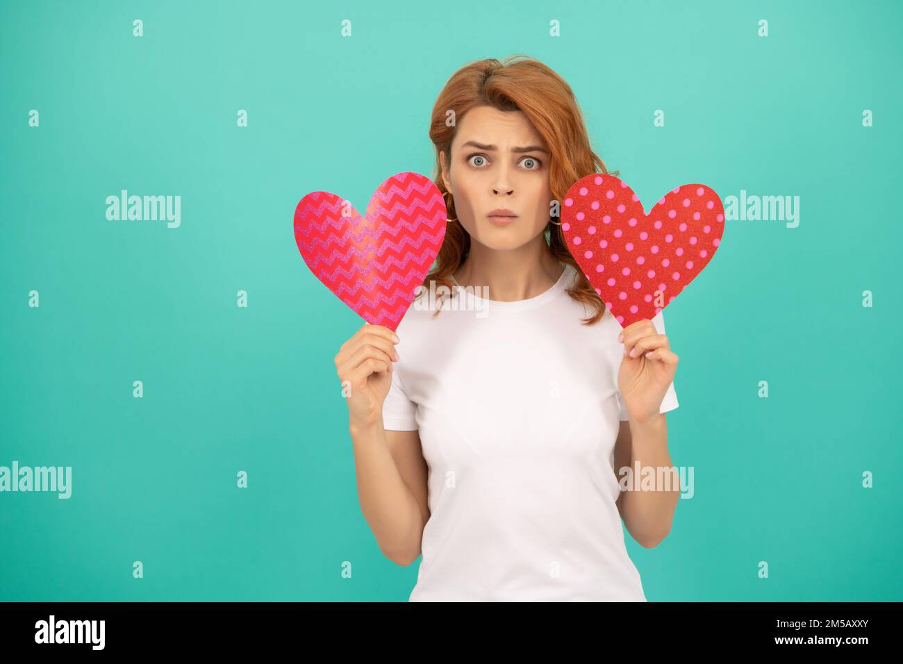confused young lady with red heart on blue background Stock Photo - Alamy