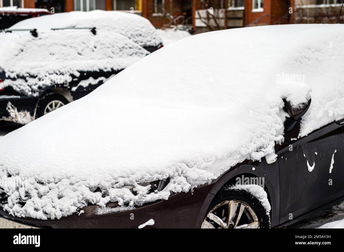 Snow-covered cars in the parking lot in the courtyard of a residential ...