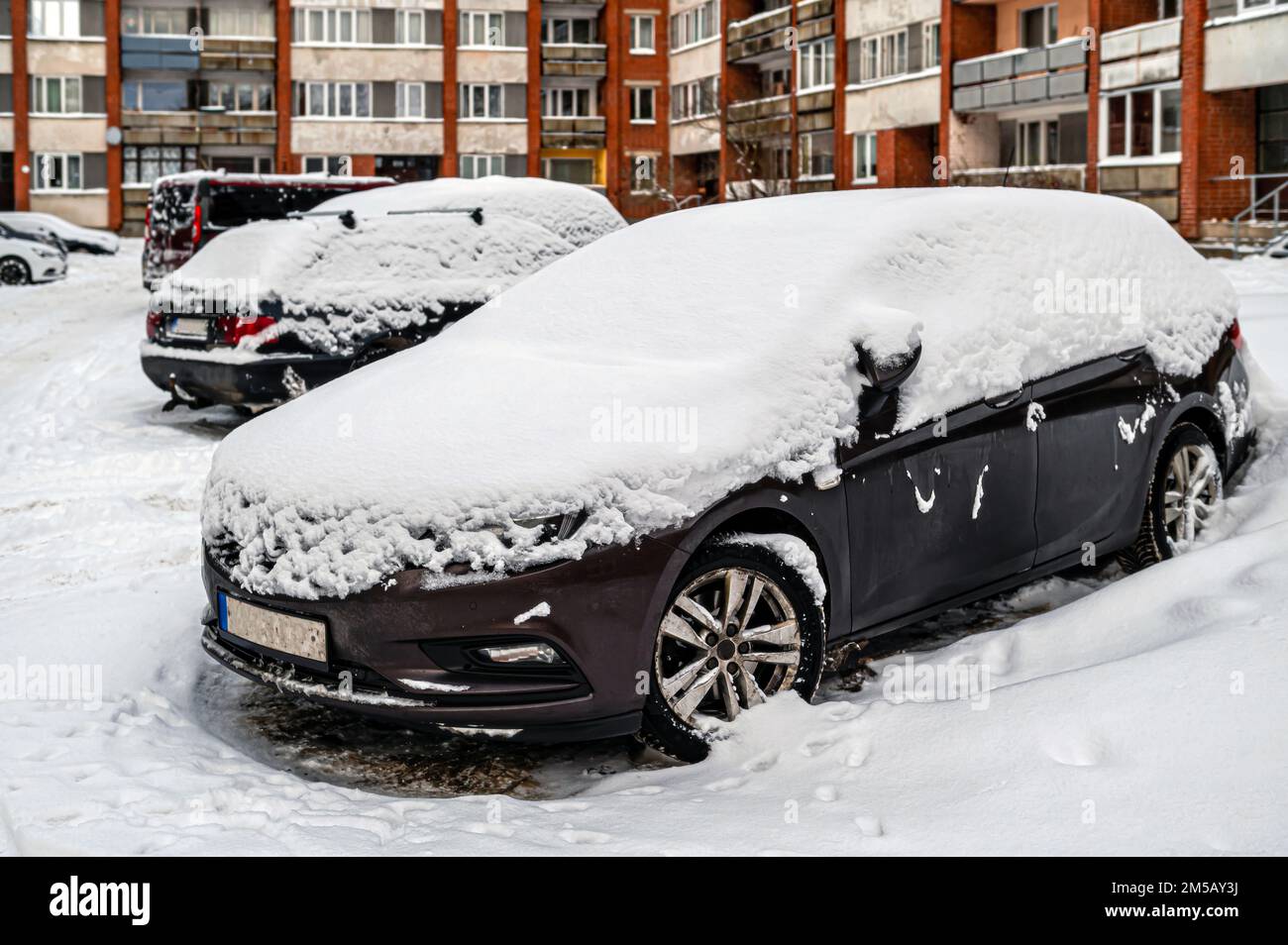 Snow-covered cars in the parking lot in the courtyard of a residential ...