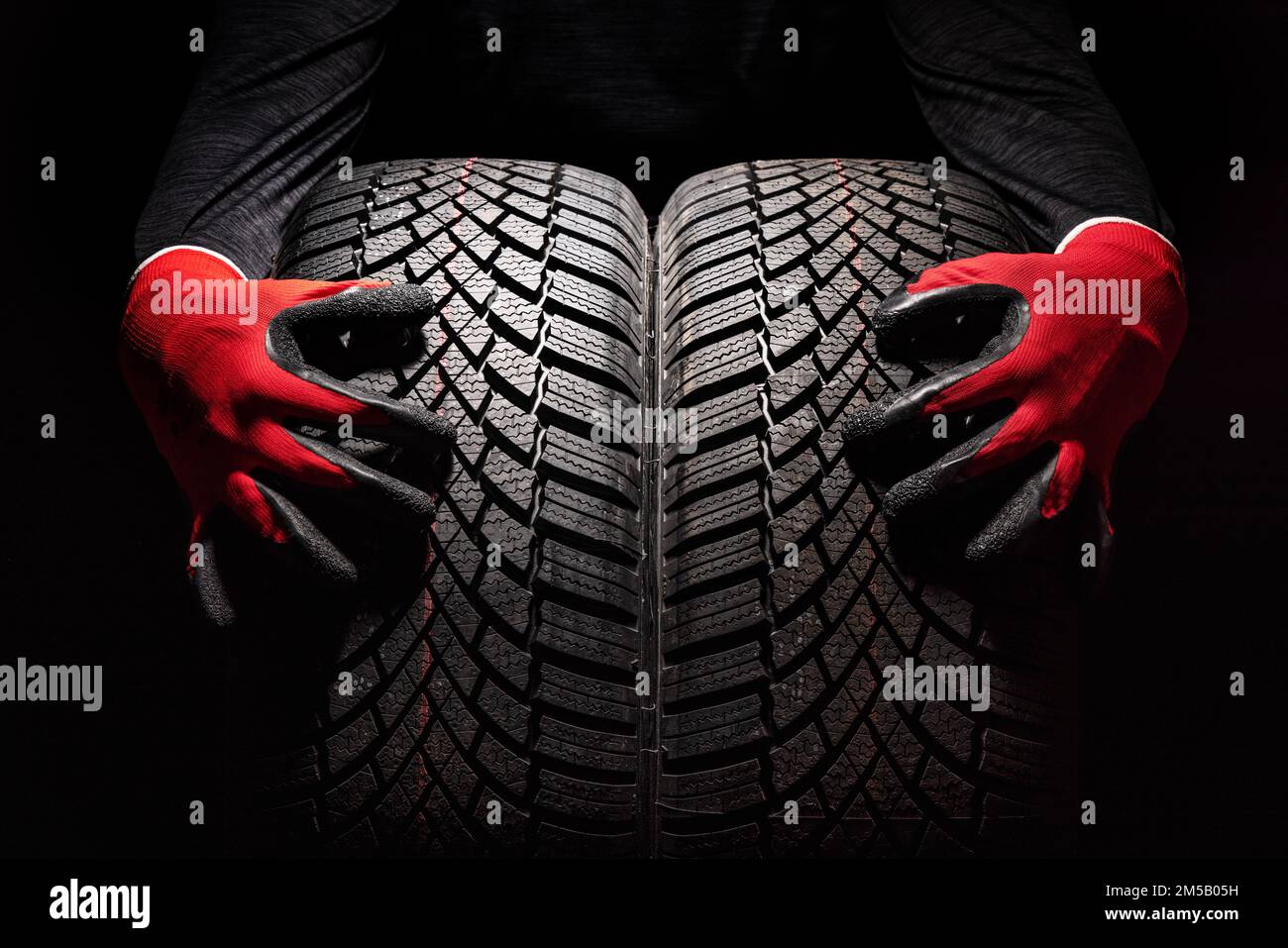 Car tire service and hands of mechanic holding new tyre on black ...