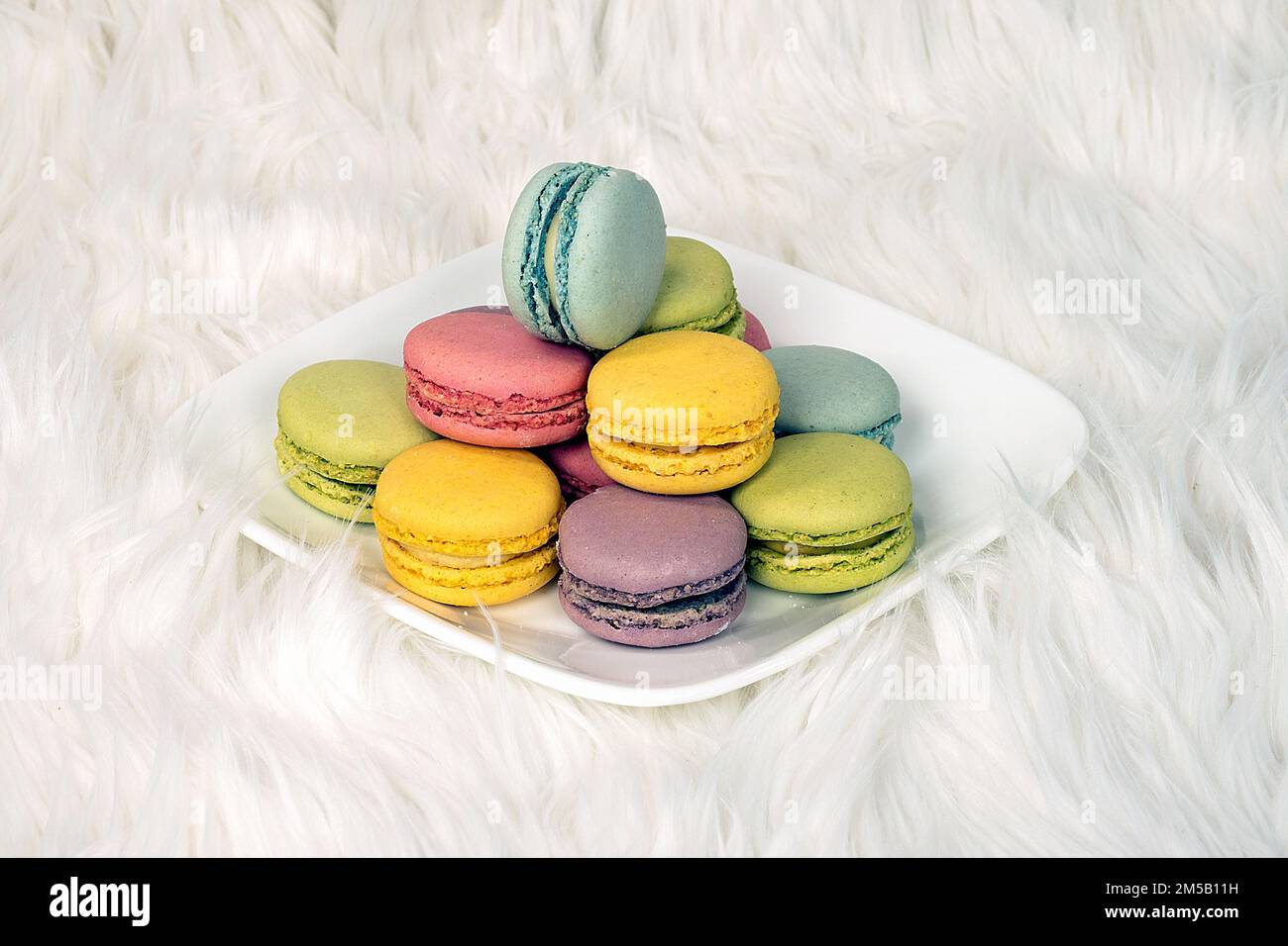 Colorful French macarons on a white square plate and fur Stock Photo ...