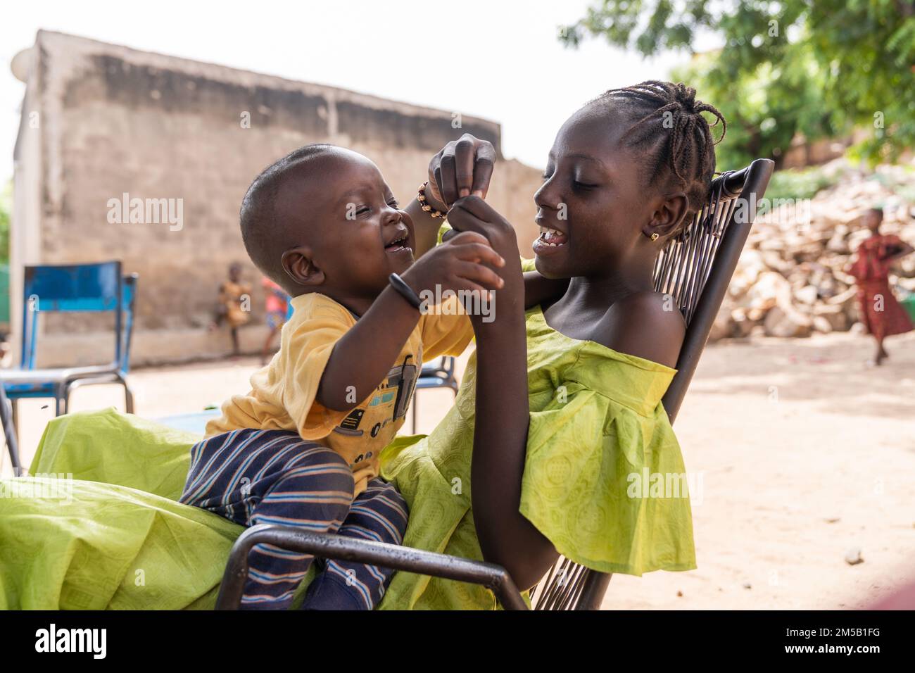 Beautiful African girl laughing and playing teasingly with her little ...