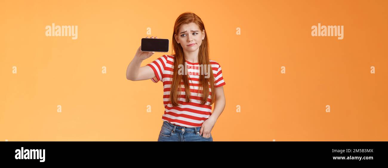 Hesitant disappointed cute redhead woman smirk displeased, hold ...