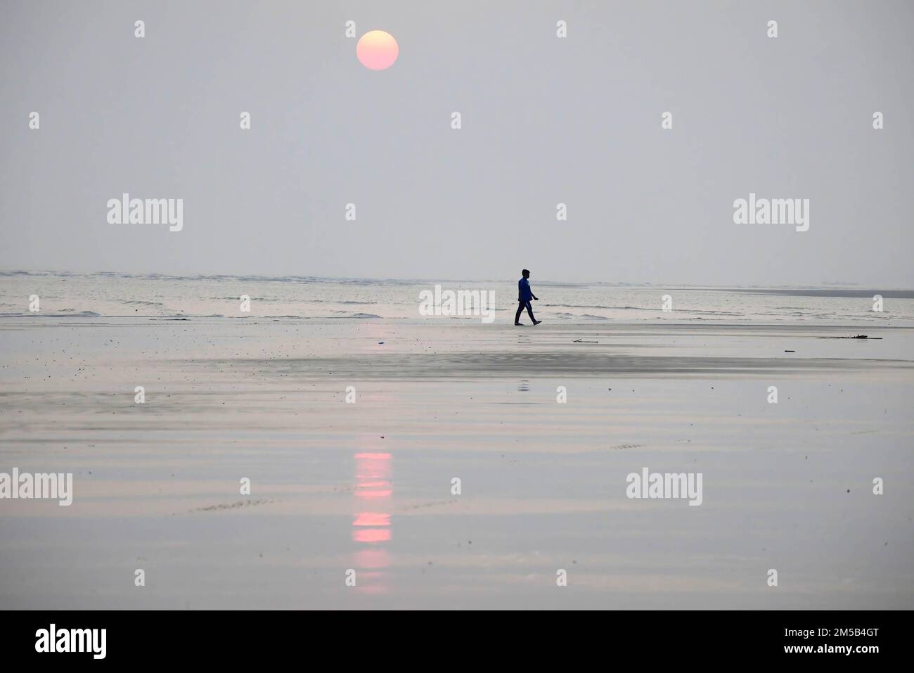 A man walks along the sea beach of Mandarmani during the evening sunset ...