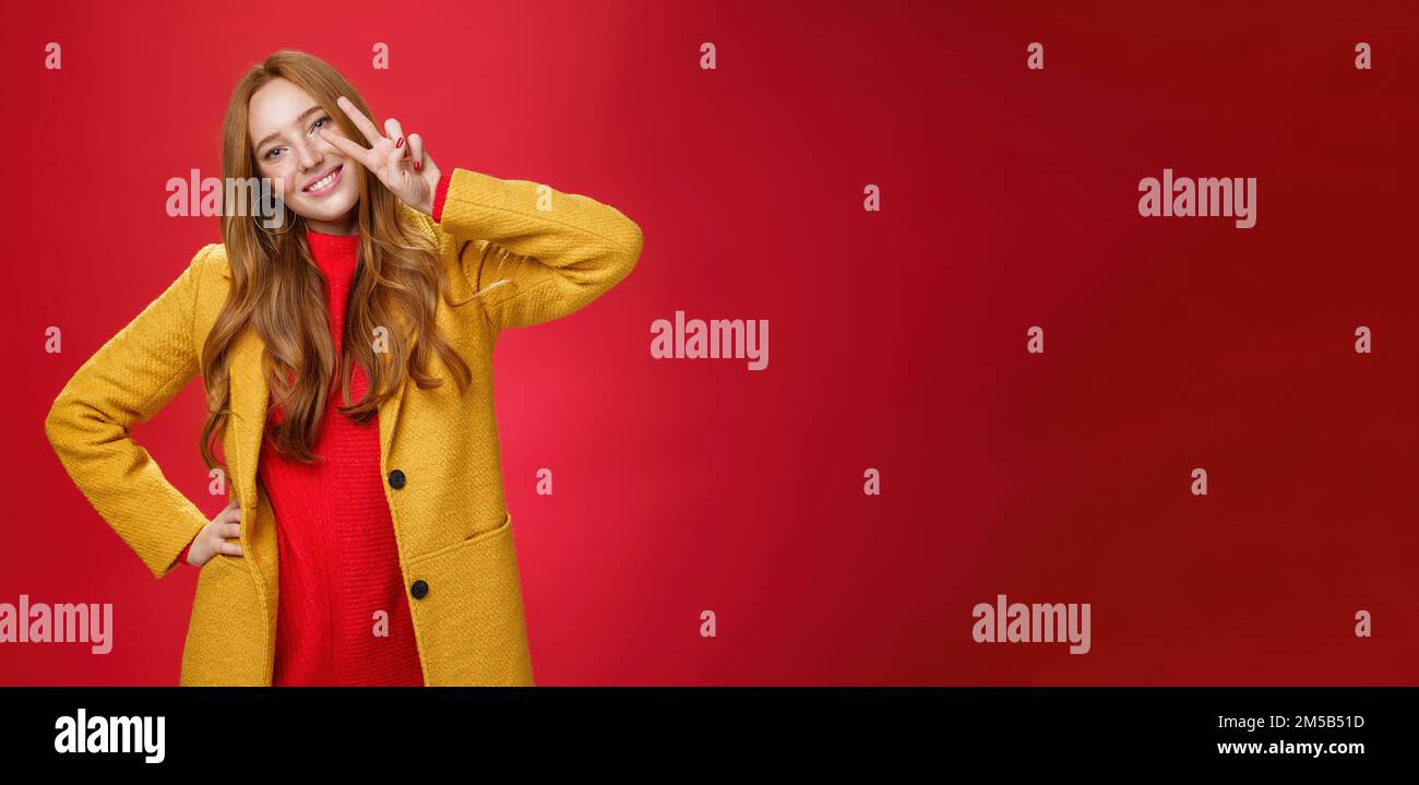 Friendly girl smiling happily, tilting head and showing peace or ...