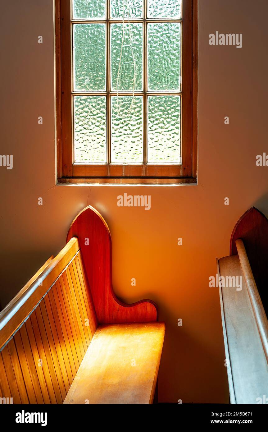 A vertical shot of the sunlit from the window over the pews sunlit in ...