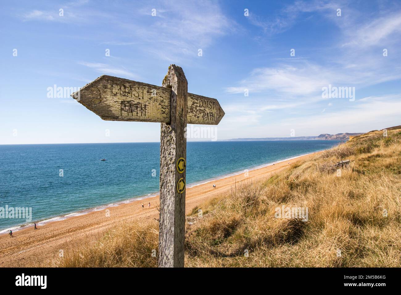A weather worn wooden sign points the way of the west Dorset coast path ...