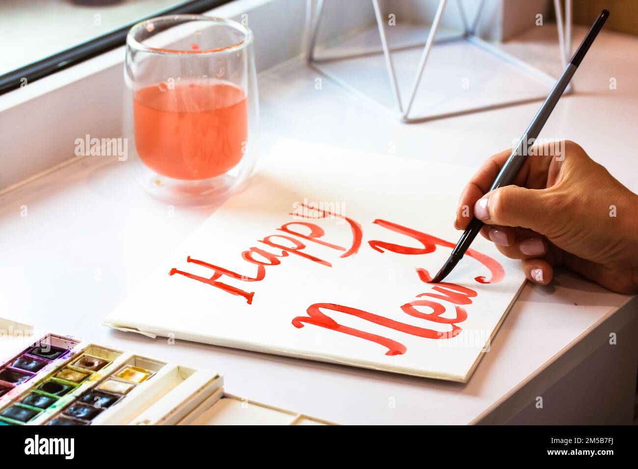 An artist drawing inscription Happy New Year with paints. A brush in ...