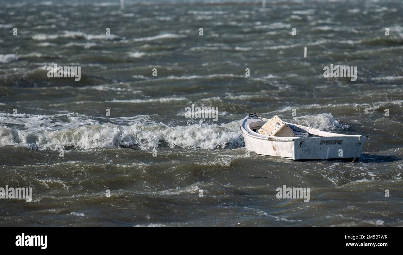 A white Wooden Rowing Boat on the shallow water of splashing sea waves ...