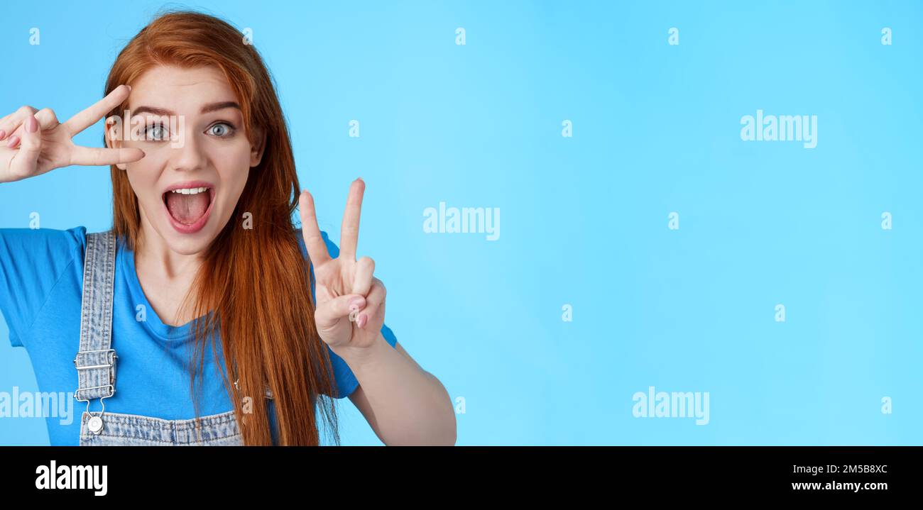 Cute excited redhead enthusiastic girl smiling, look joyful show peace ...