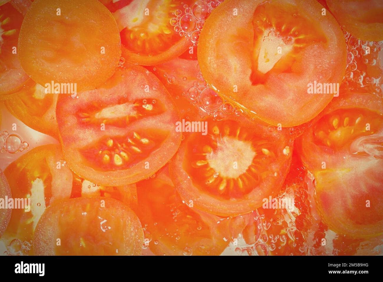 Tomato close-up in liquid with bubbles. Slices of red ripe tomato in ...