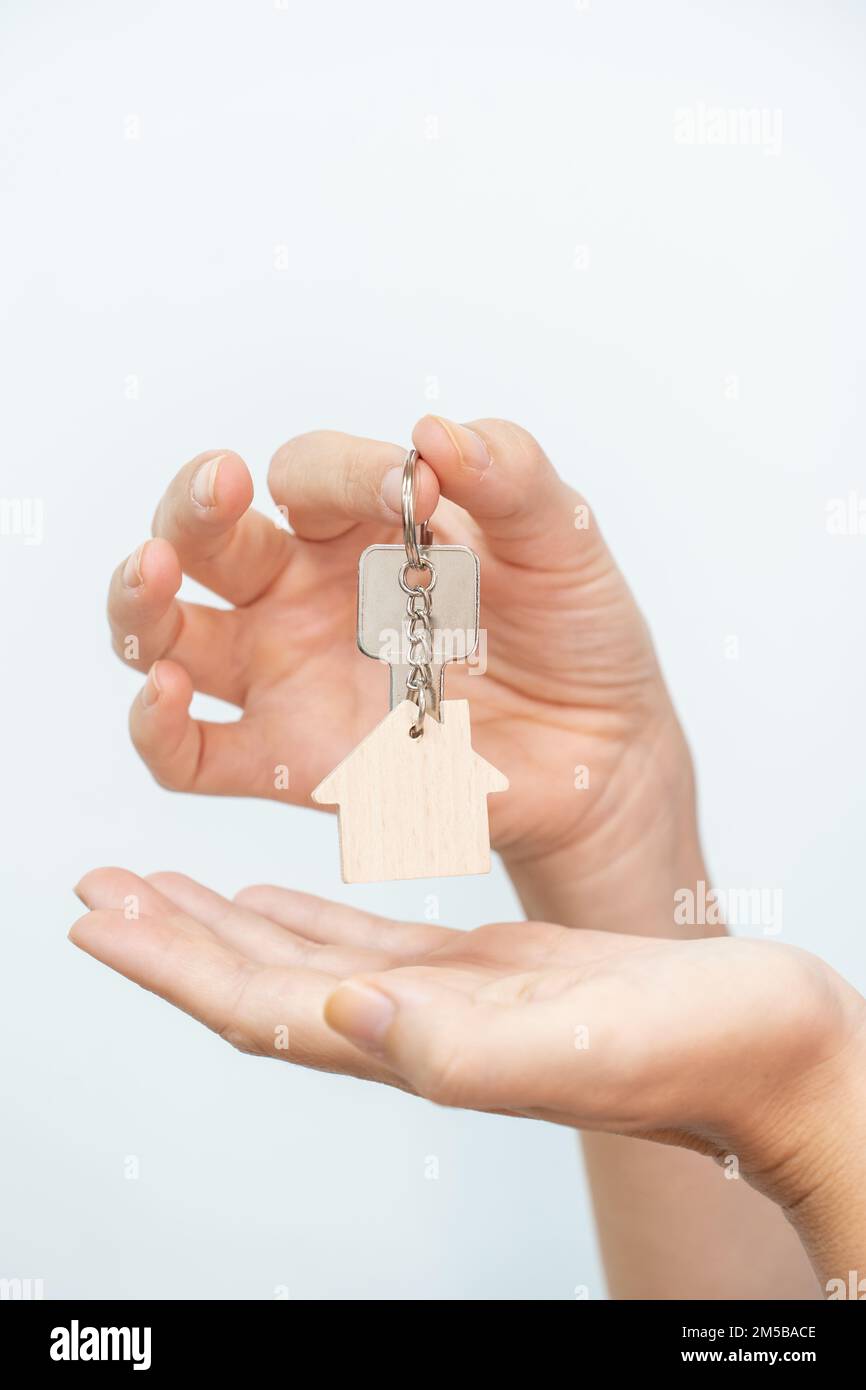 Hands holding house key on white background closeup - real state moving ...