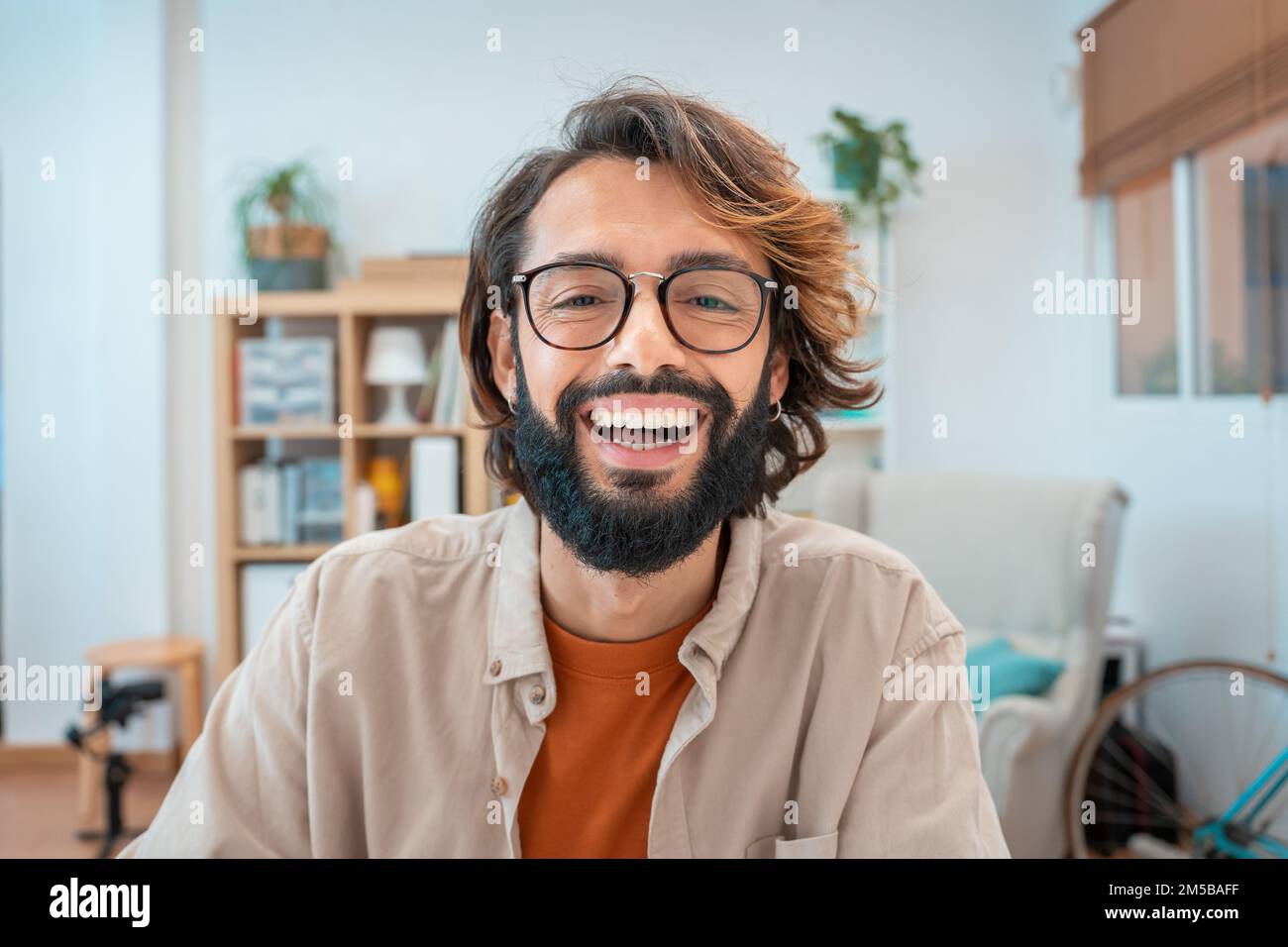 Portrait of freelancer man at home office, looking and smiling at ...