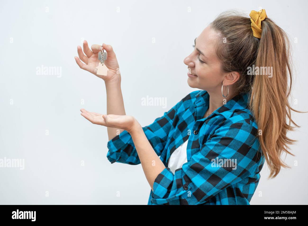Young smiling woman holding house keys standing against white ...