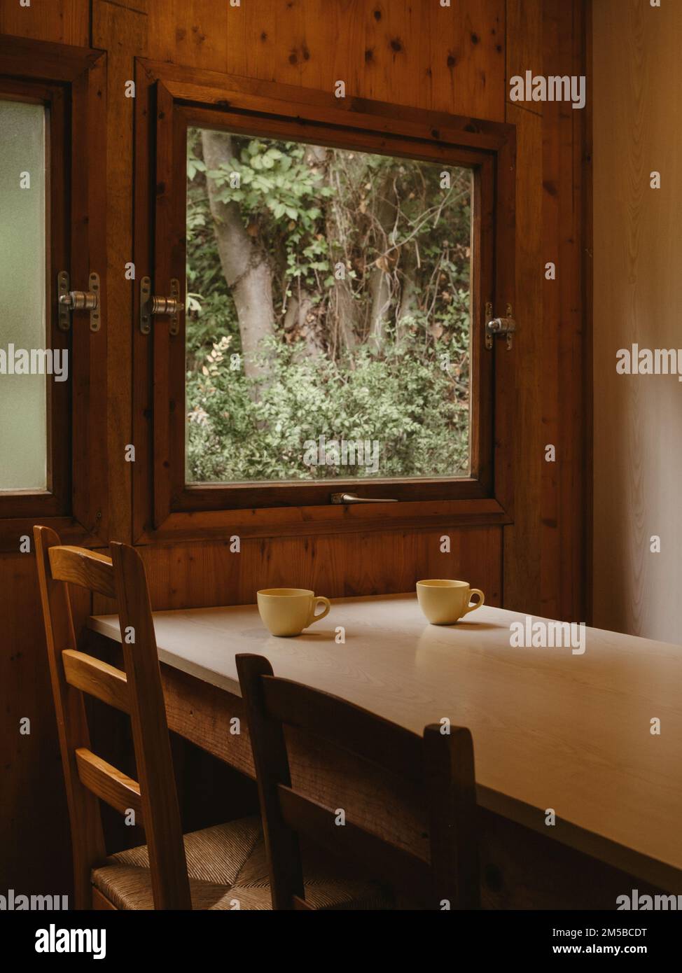 A vertical shot of a wooden table placed next to a window in a cozy ...