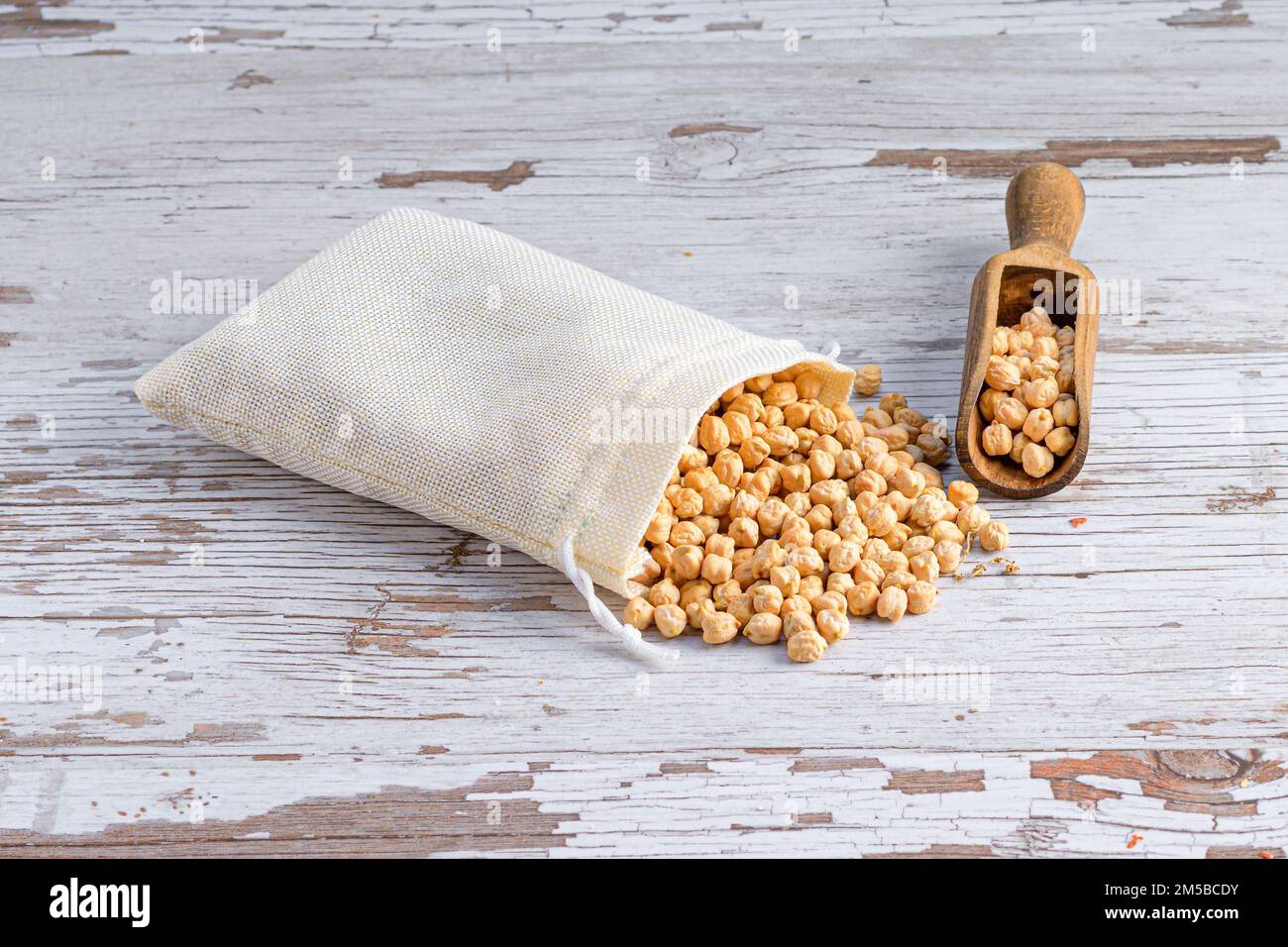 A closeup shot of chickpeas placed in a sack and a dustpan and placed ...