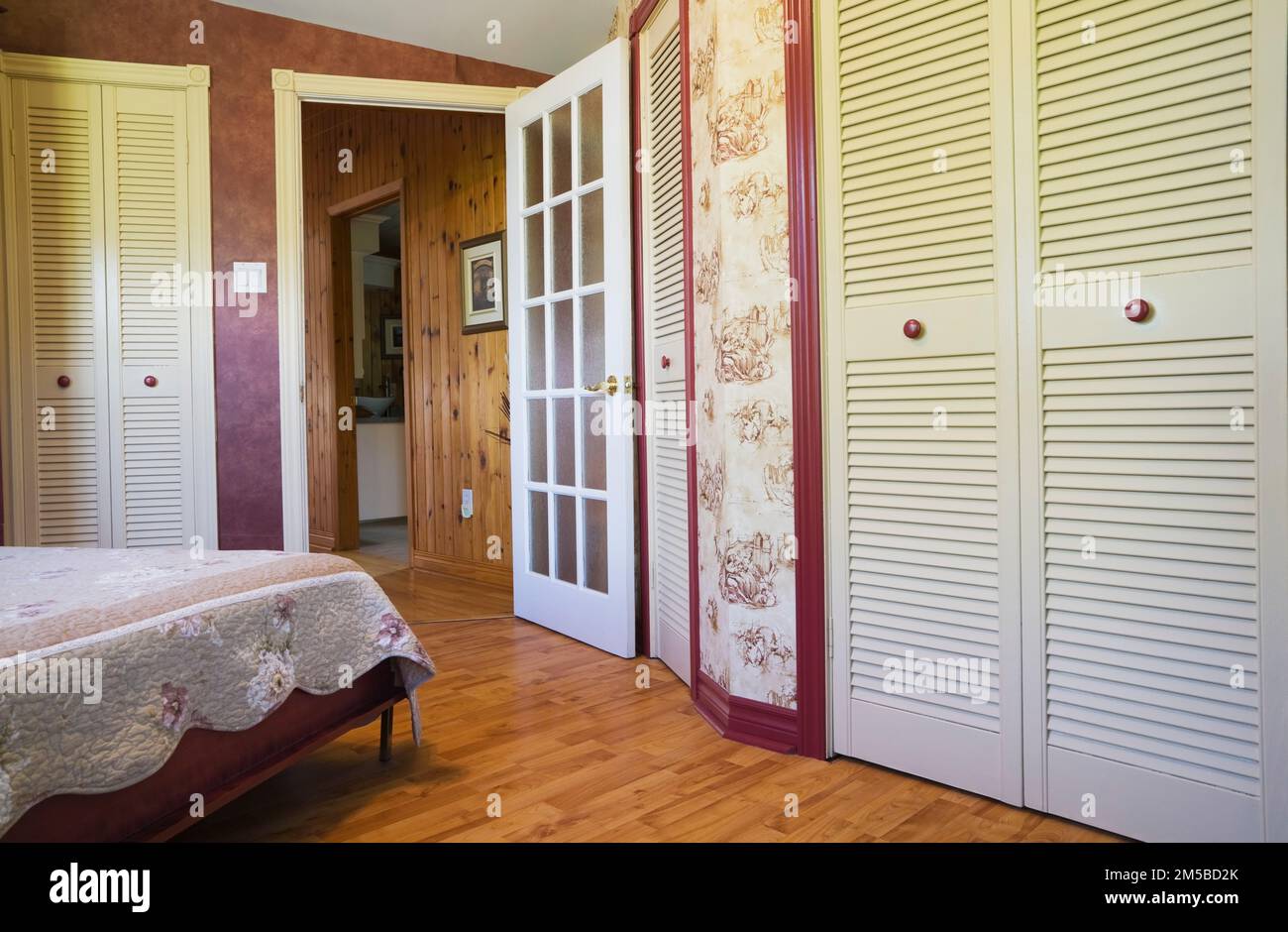 Cream colored louvered wooden closet doors and French door in guest ...