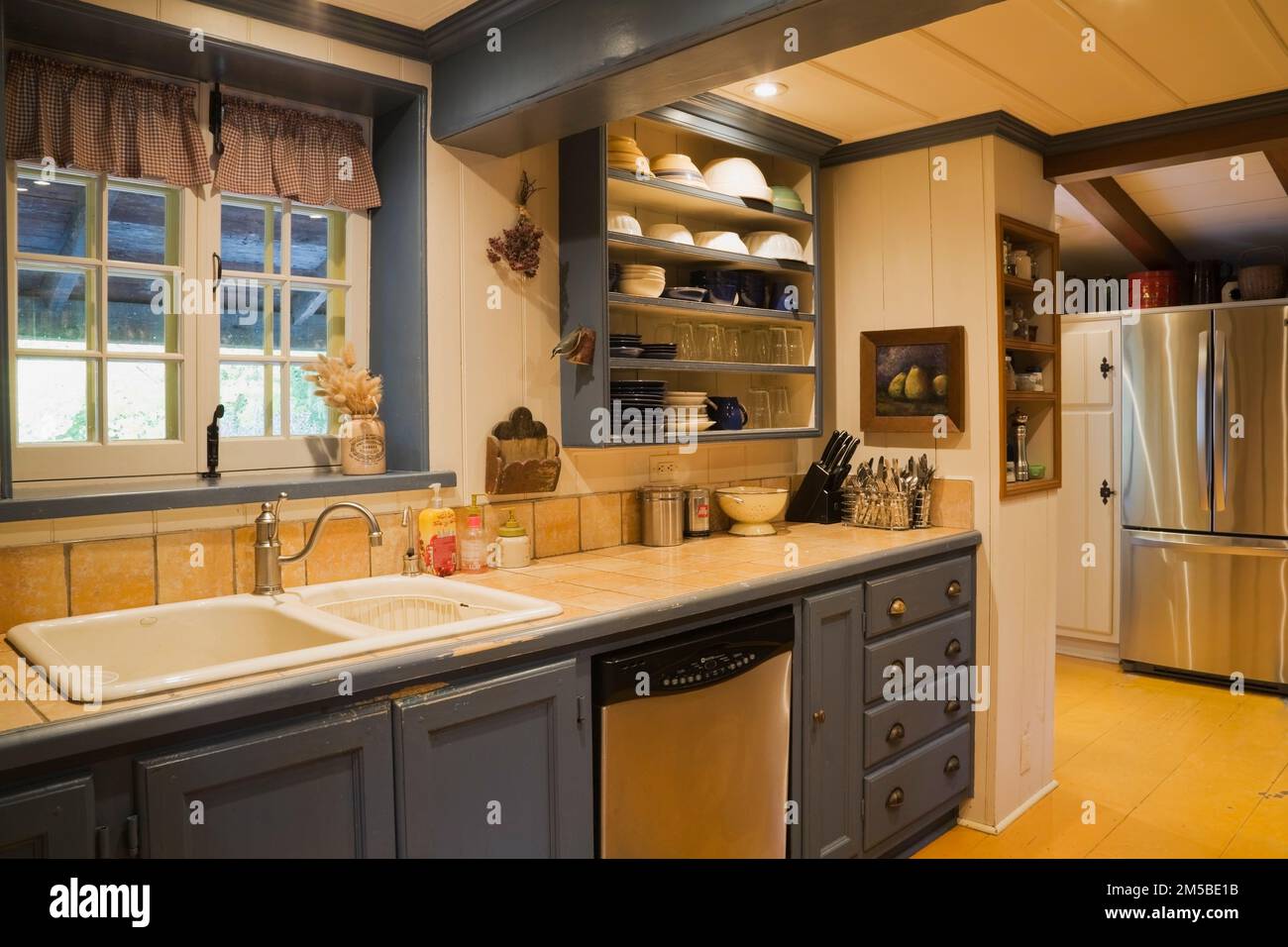 Blue cabinets and tan ceramic countertop in kitchen with yellow painted ...