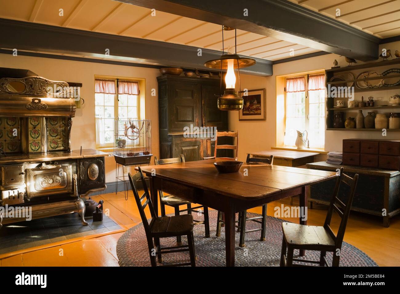 Antique wooden table and chairs on top of woven oval rug in dining room ...
