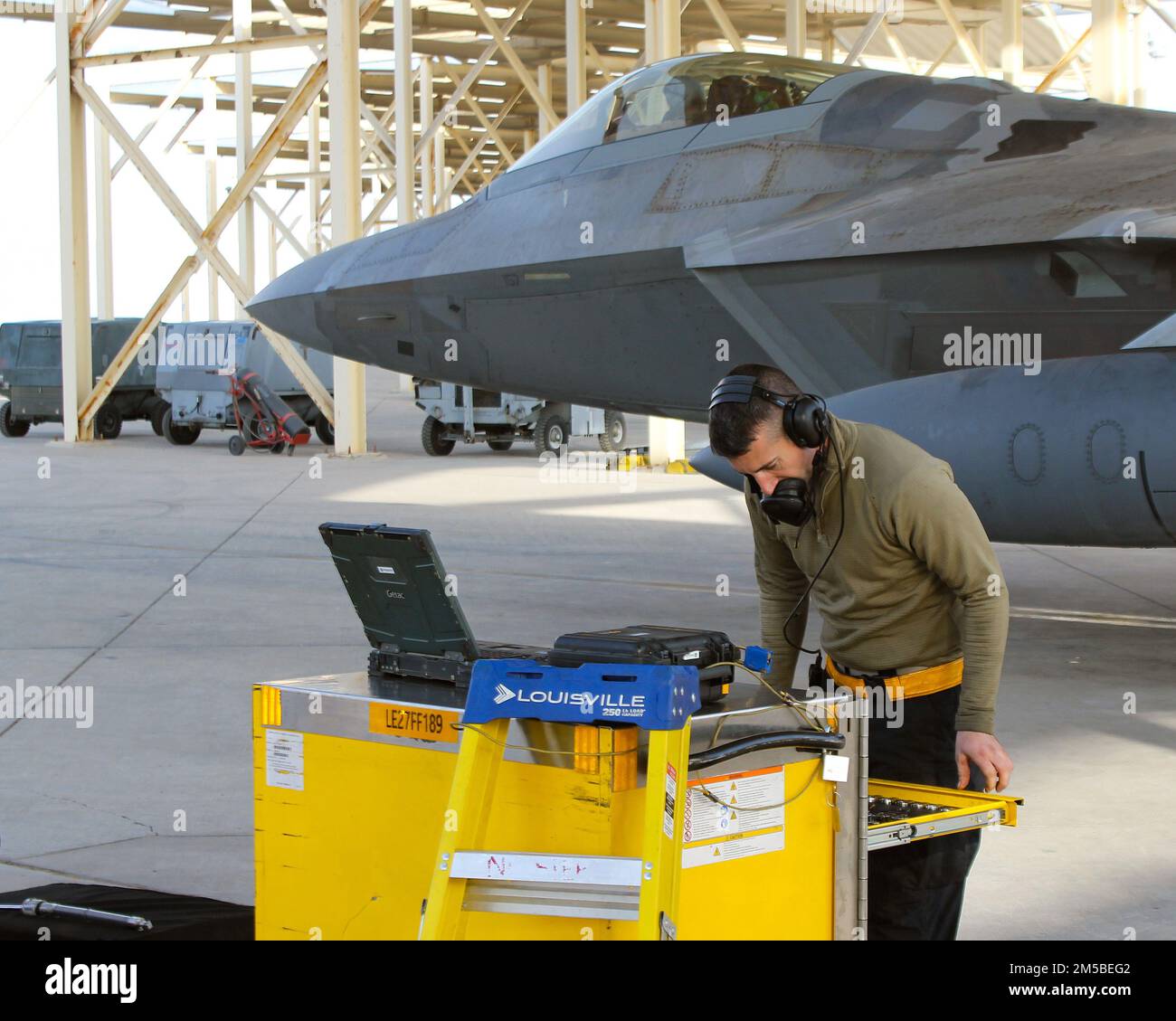 An F-22 Raptor crew chief, assigned to the 1st Fighter Wing, goes ...