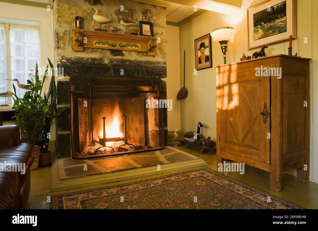 Lit wood burning stone fireplace and small wooden antique armoire in ...