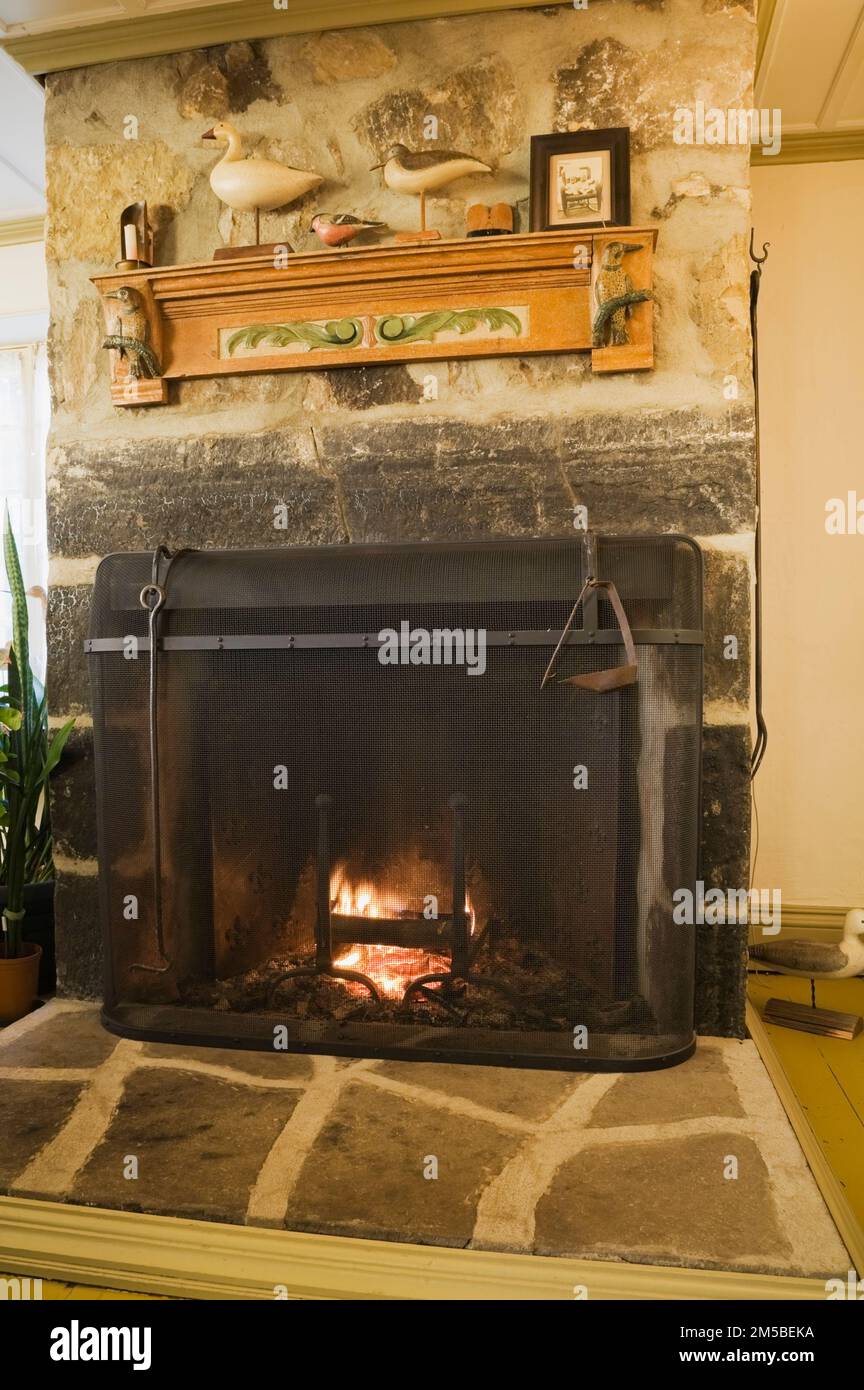 Lit wood burning stone fireplace in living room inside old 1722 French ...