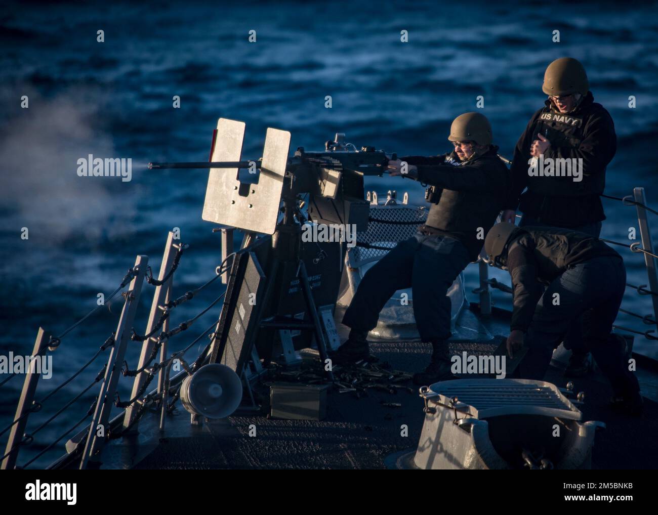 A Sailor fires a .50-caliber machine gun at simulated enemy small boats ...