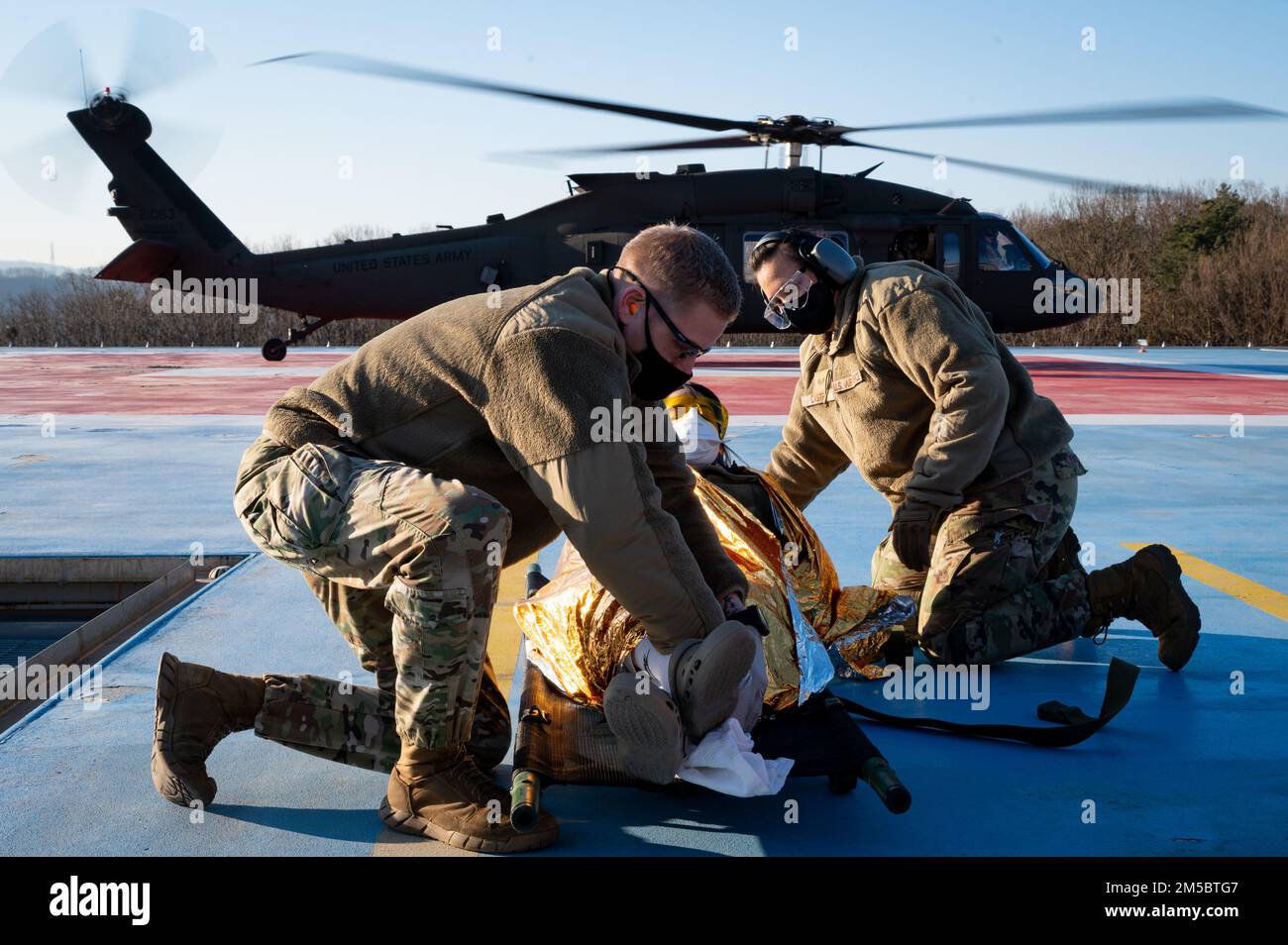 U.S. Air Force Airmen wrap a patient in an emergency foil blanket ...
