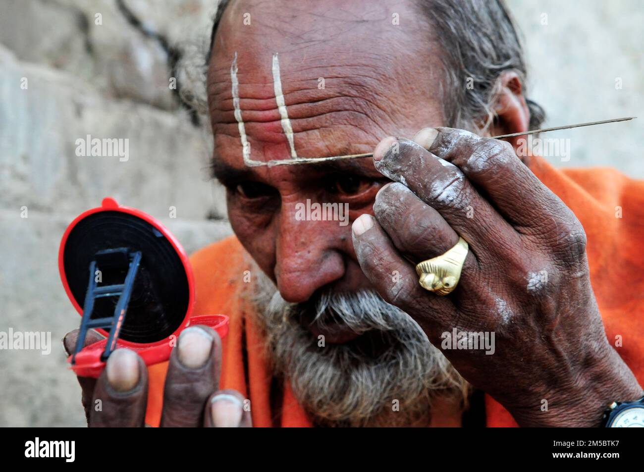 A sadhu painting his forehead with Tilaka on the Mallick Ghat by the ...