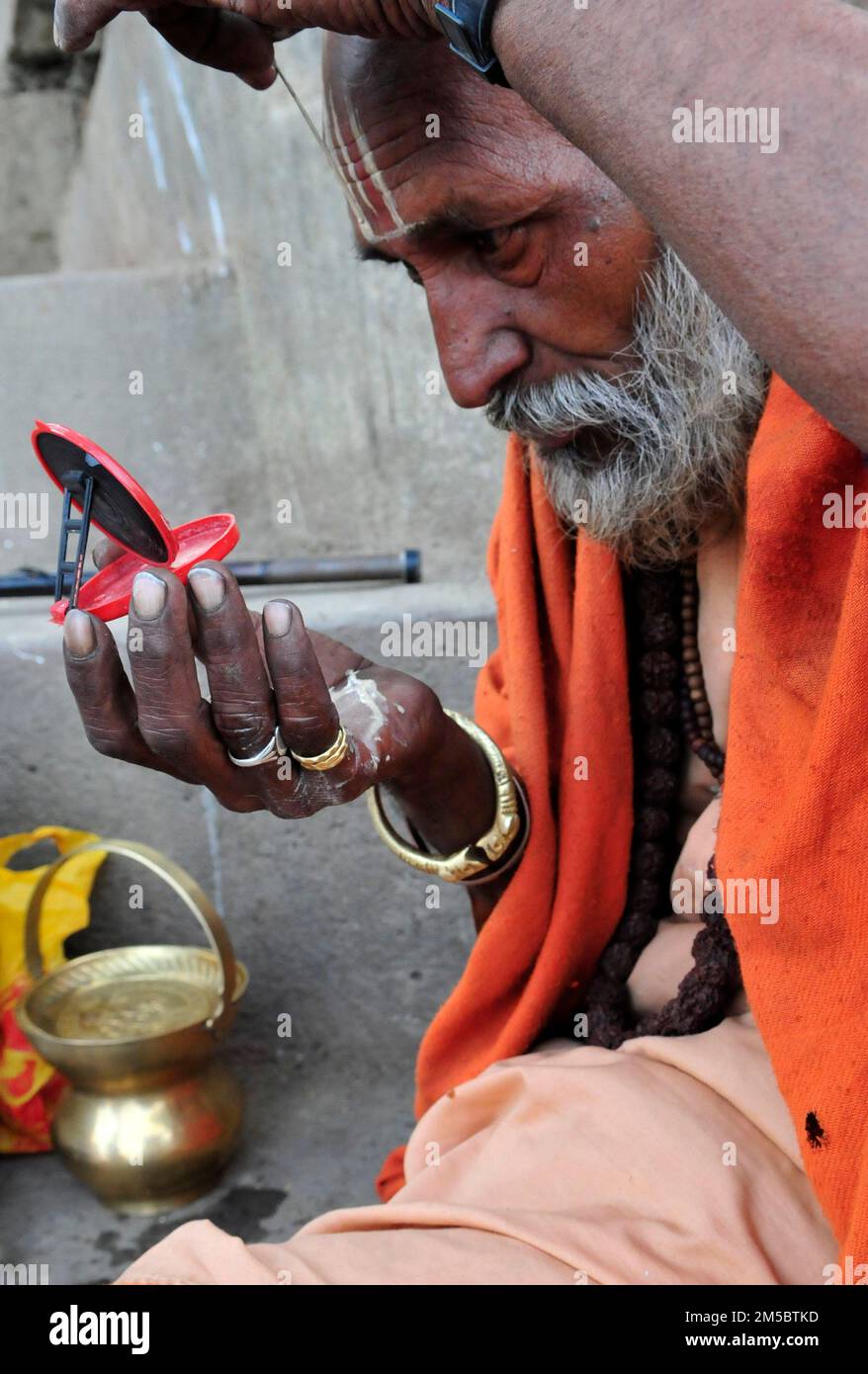 A sadhu painting his forehead with Tilaka on the Mallick Ghat by the ...