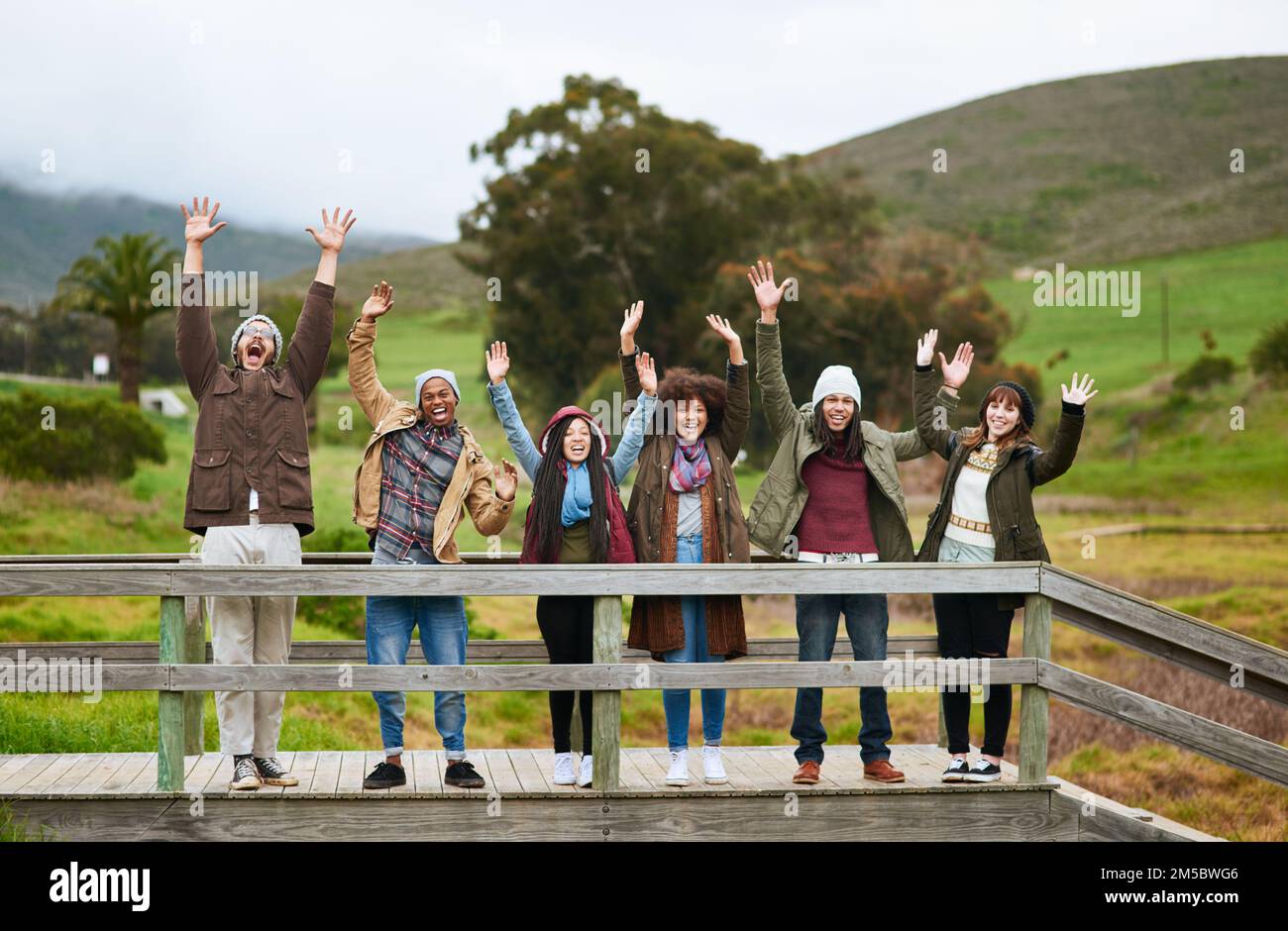 The fun just never stops. Portrait of a group of friends raising their ...