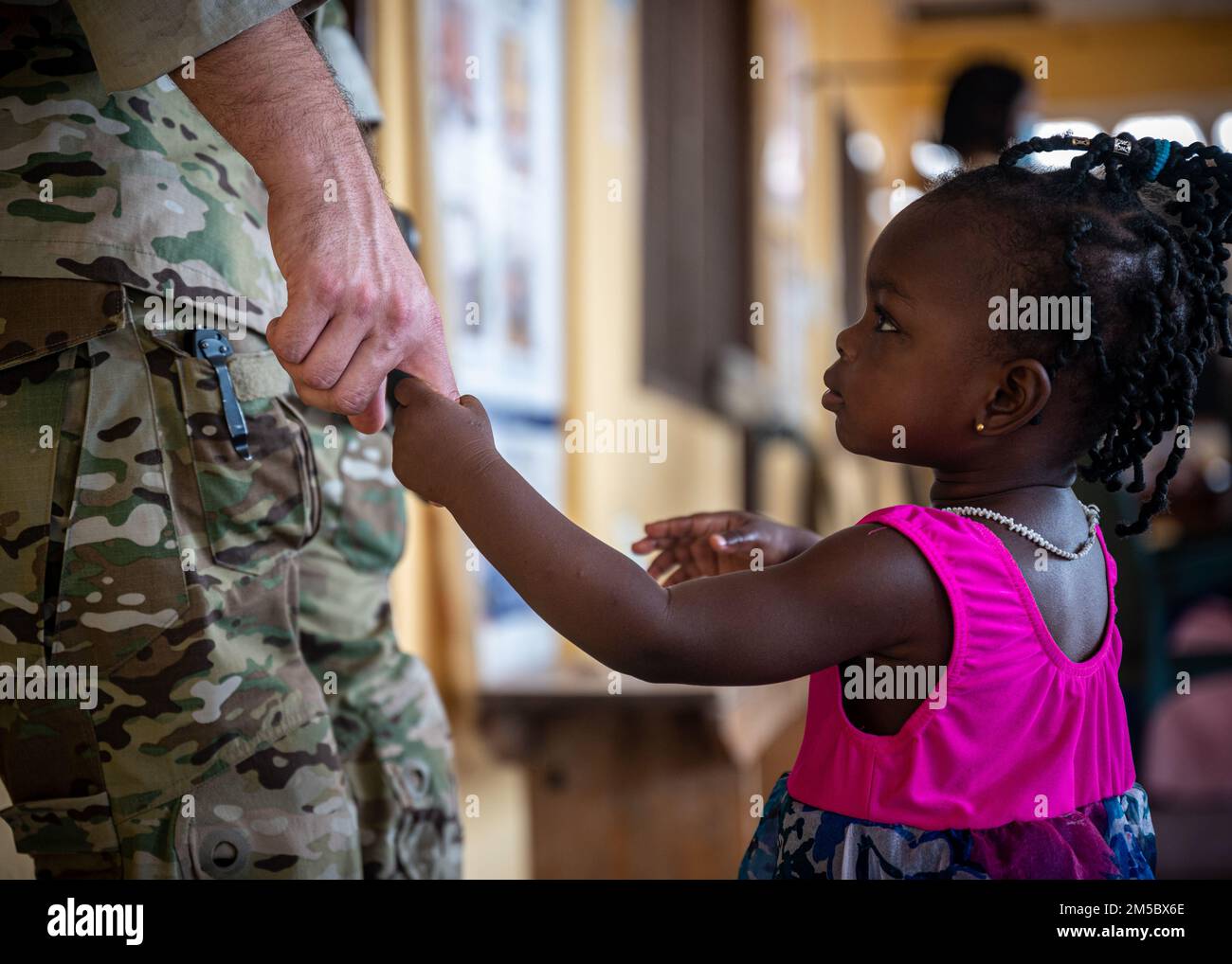 A Ghanaian child holds the finger of a U.S. Army Civil Military Support ...