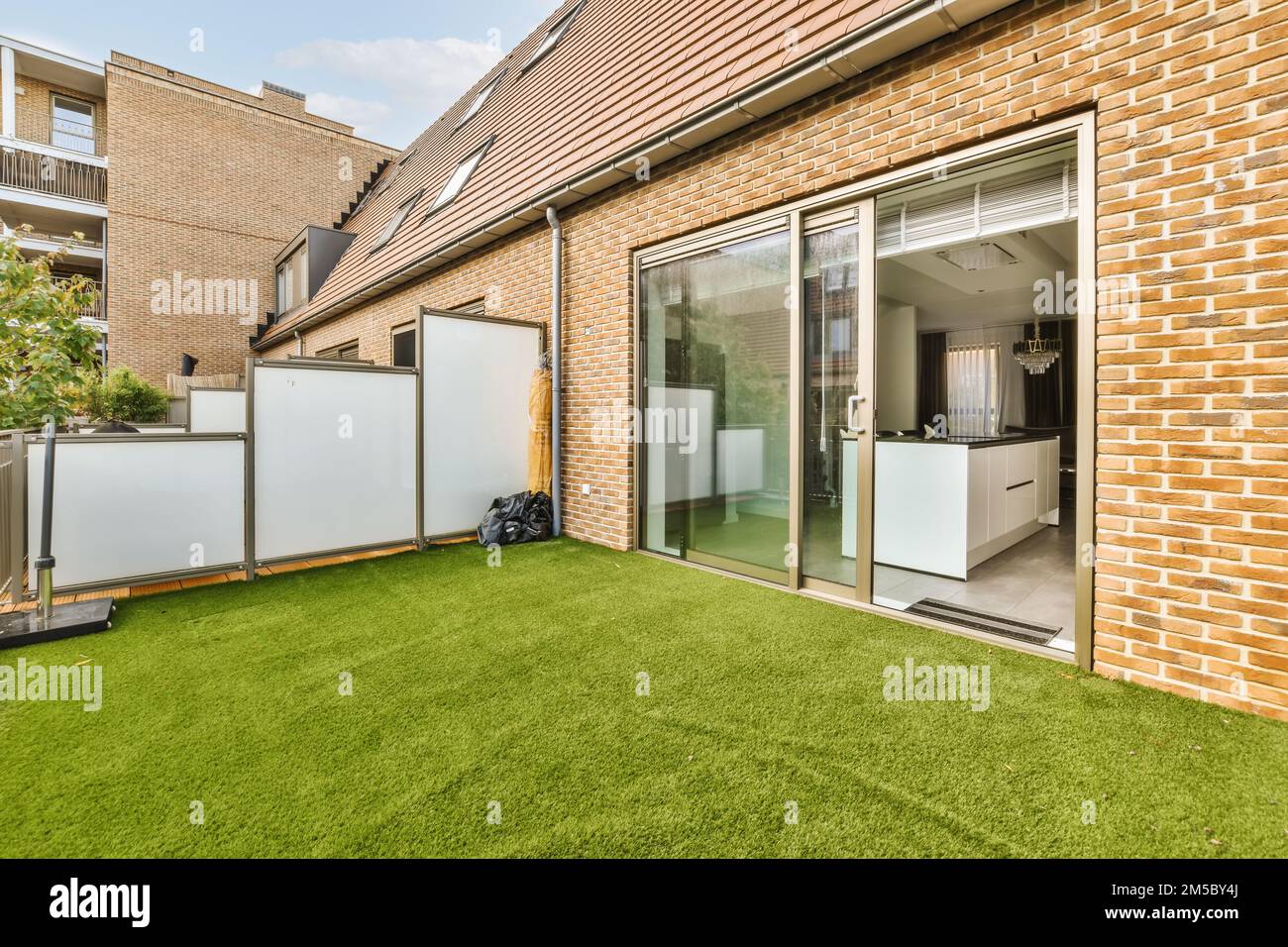an outside area with green grass and brick walls, including sliding ...