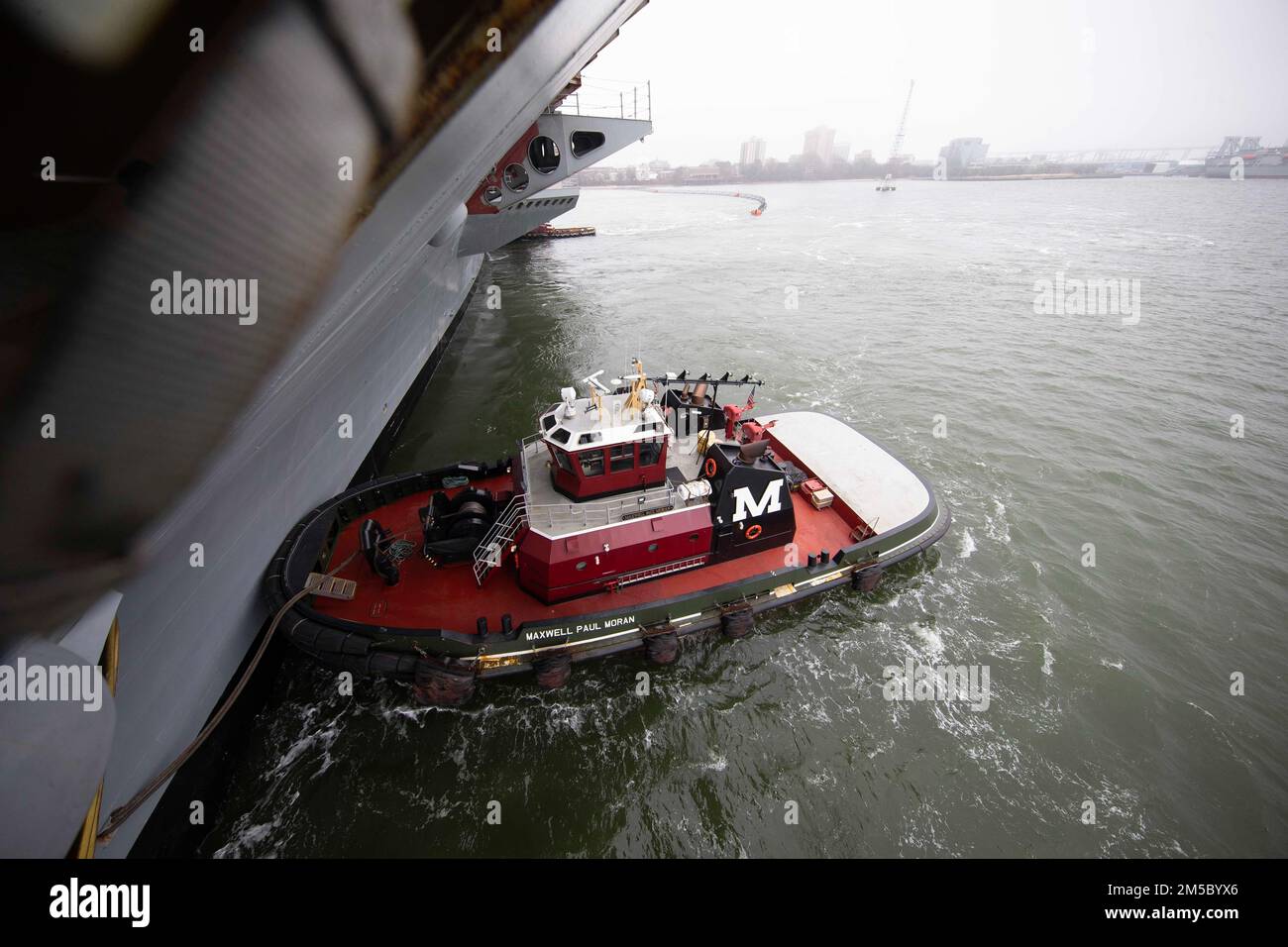 A tugboat maneuvers USS Gerald R. Ford (CVN 78) into the James river ...
