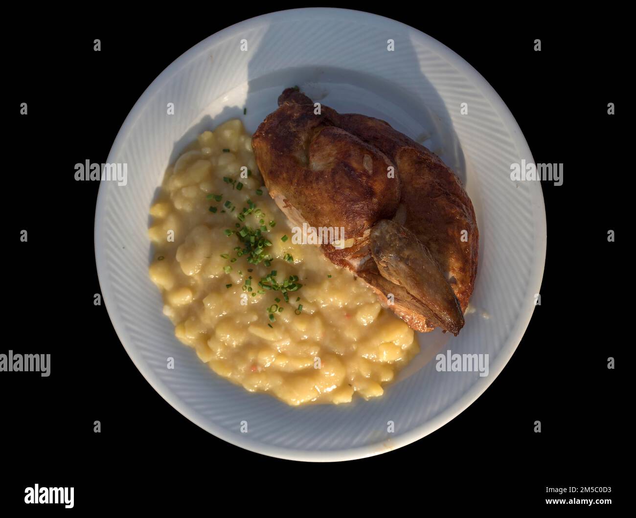 Half baked chicken with potato salad on a black background, Bavaria ...