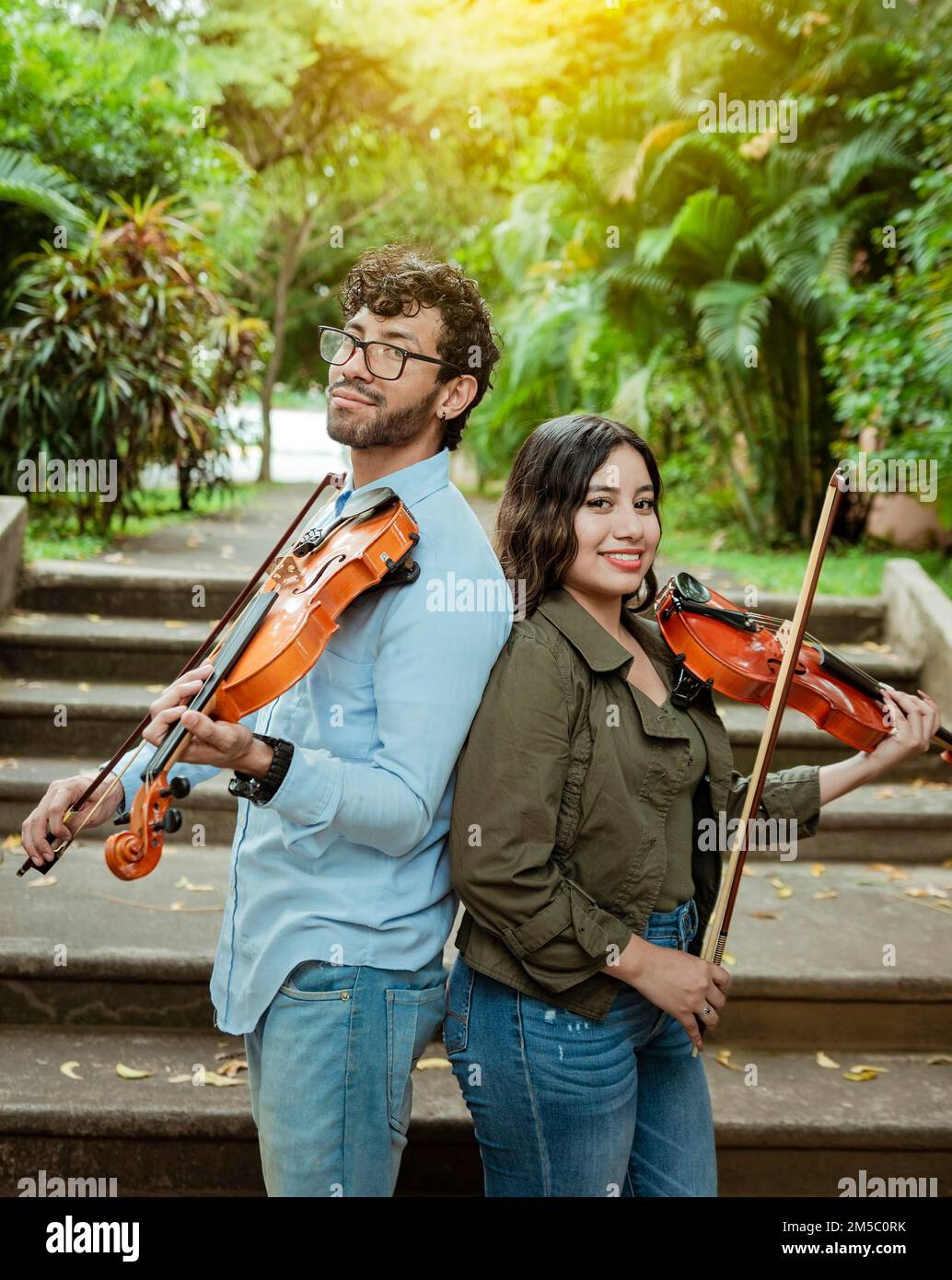 Portrait of two young violists back to back outdoors. Portrait of ...