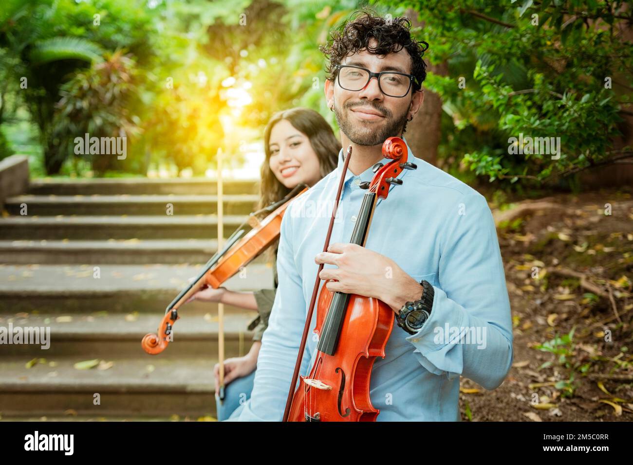 Portrait of two young violists sitting outside. Man and woman violinist ...