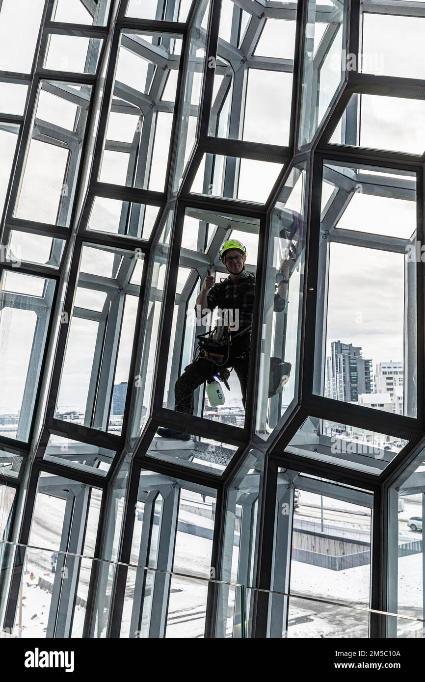 Window cleaners cleaning the glass facade of the Harpa Concert Hall and ...
