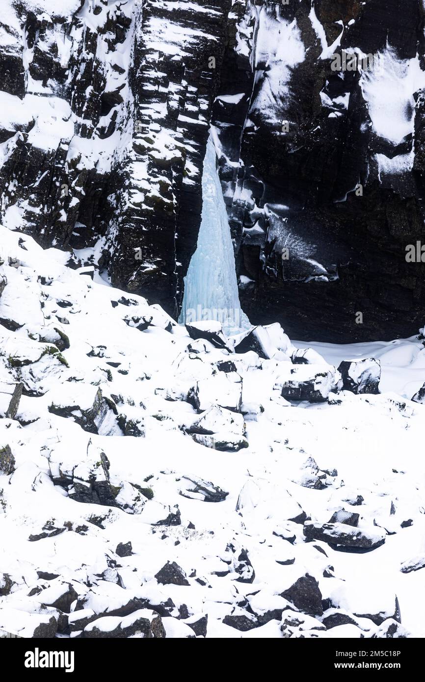 Frozen waterfall, Folaldafoss, snowy rock face and snowy landscape ...