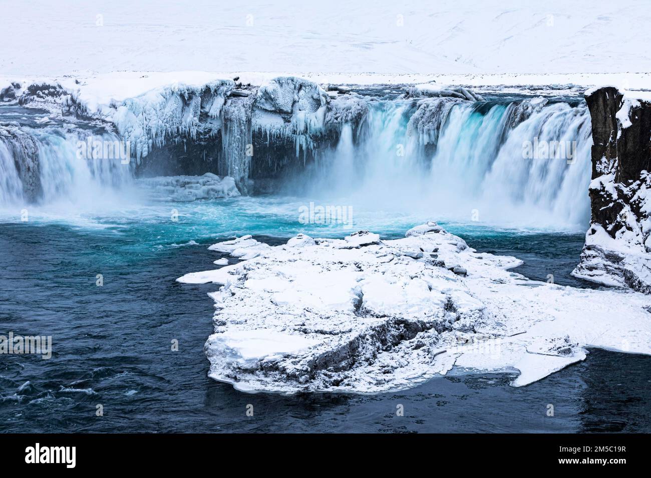 Ice layer in the river Skialfandaljot, behind it the waterfall Godafoss ...