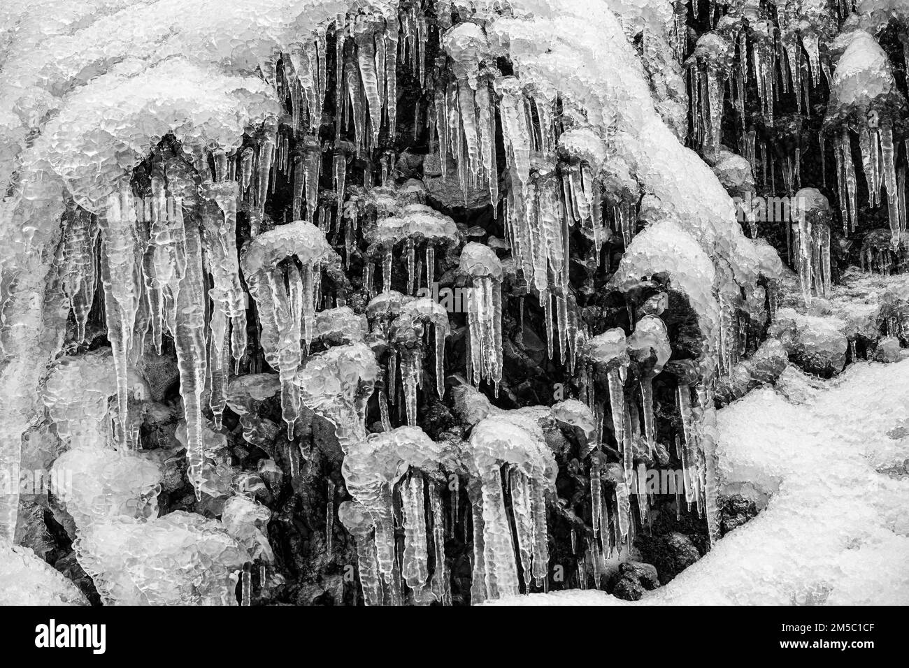 Icicles on the rock face at Skogafoss waterfall, black and white photo ...