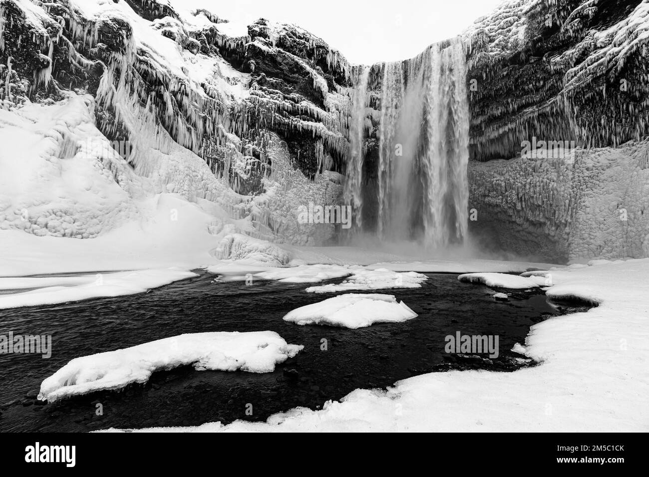 Skogafoss waterfall with icy and snowy rock face, black and white photo ...
